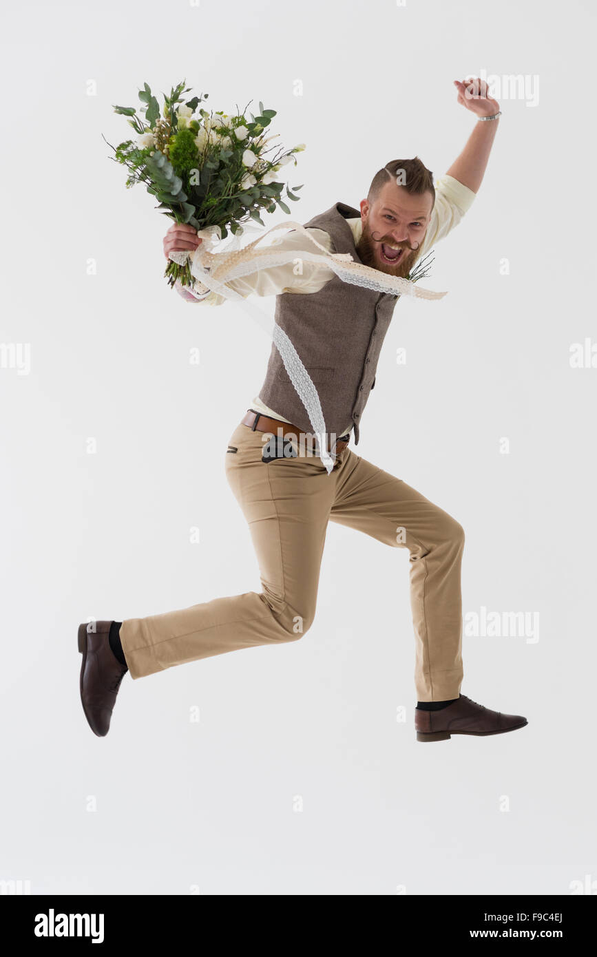 Full length portrait of modern groom dancing and jumping with wedding ...