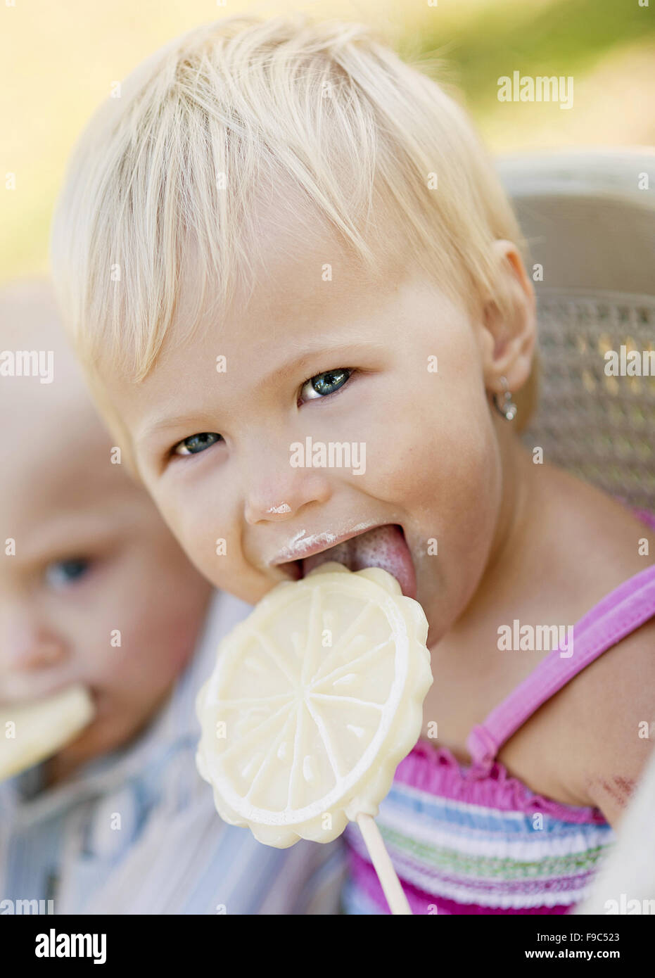 Two happy kids eating lolly in the park Stock Photo - Alamy