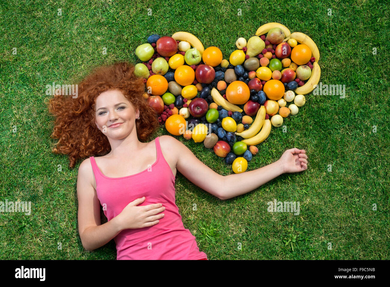 Girl with fruit lying on the grass Stock Photo - Alamy