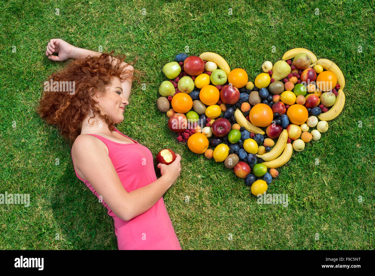 Girl with fruit lying on the grass Stock Photo - Alamy