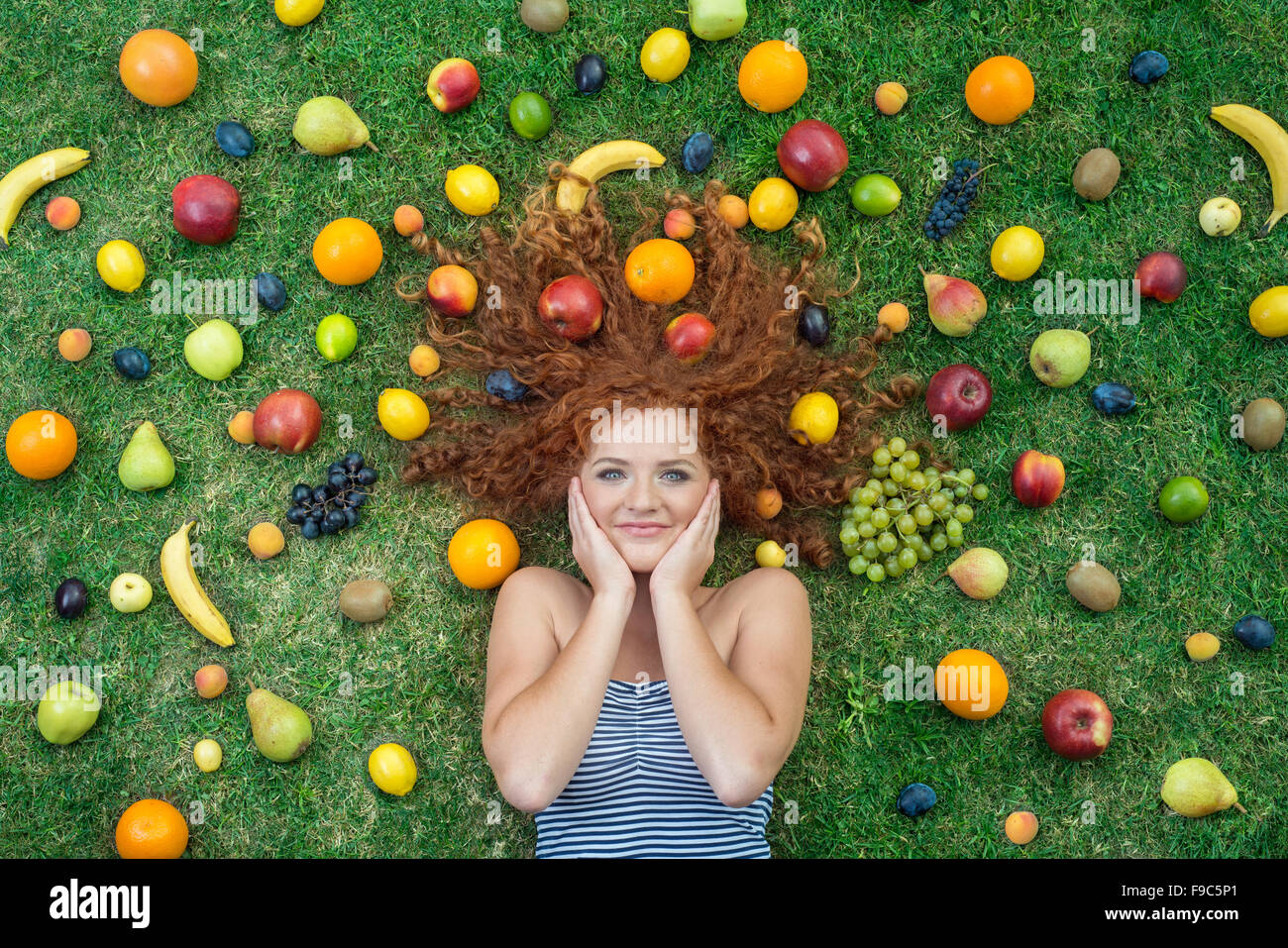 Girl with fruit lying on the grass Stock Photo - Alamy