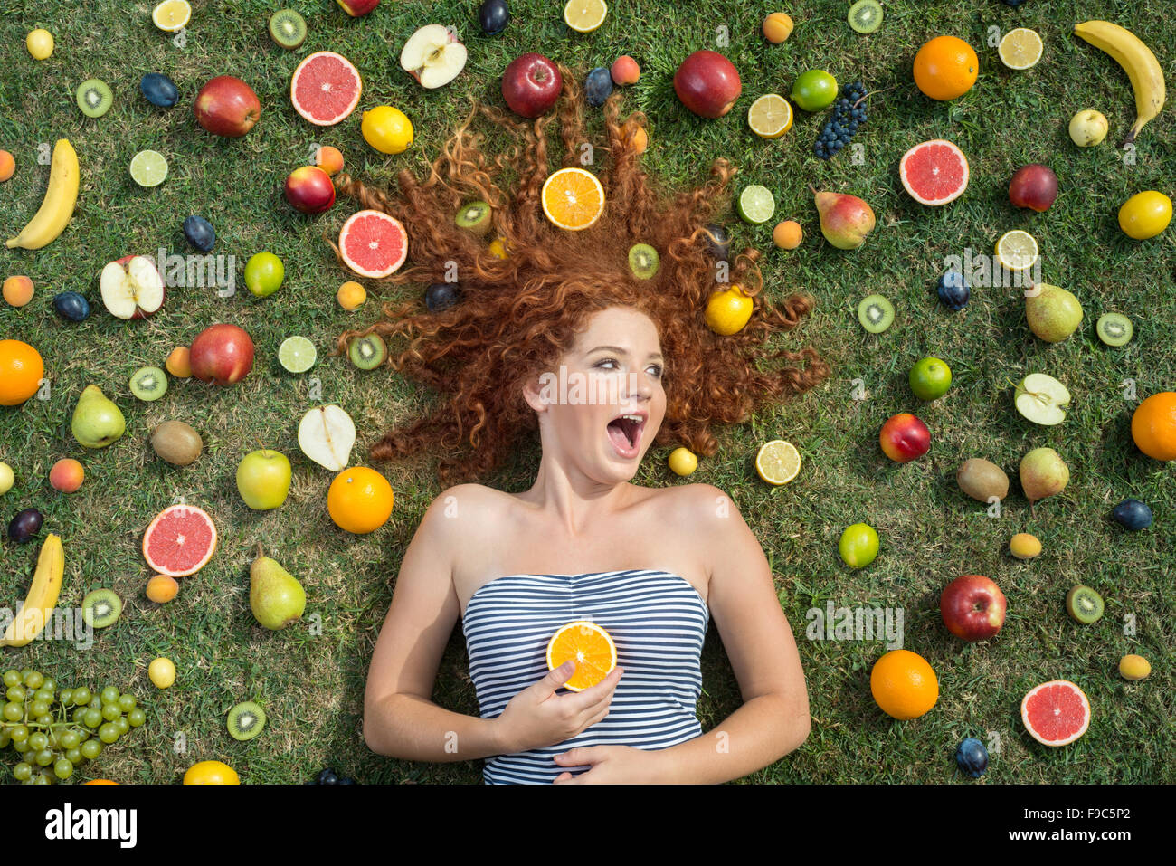 Girl with fruit lying on the grass Stock Photo - Alamy