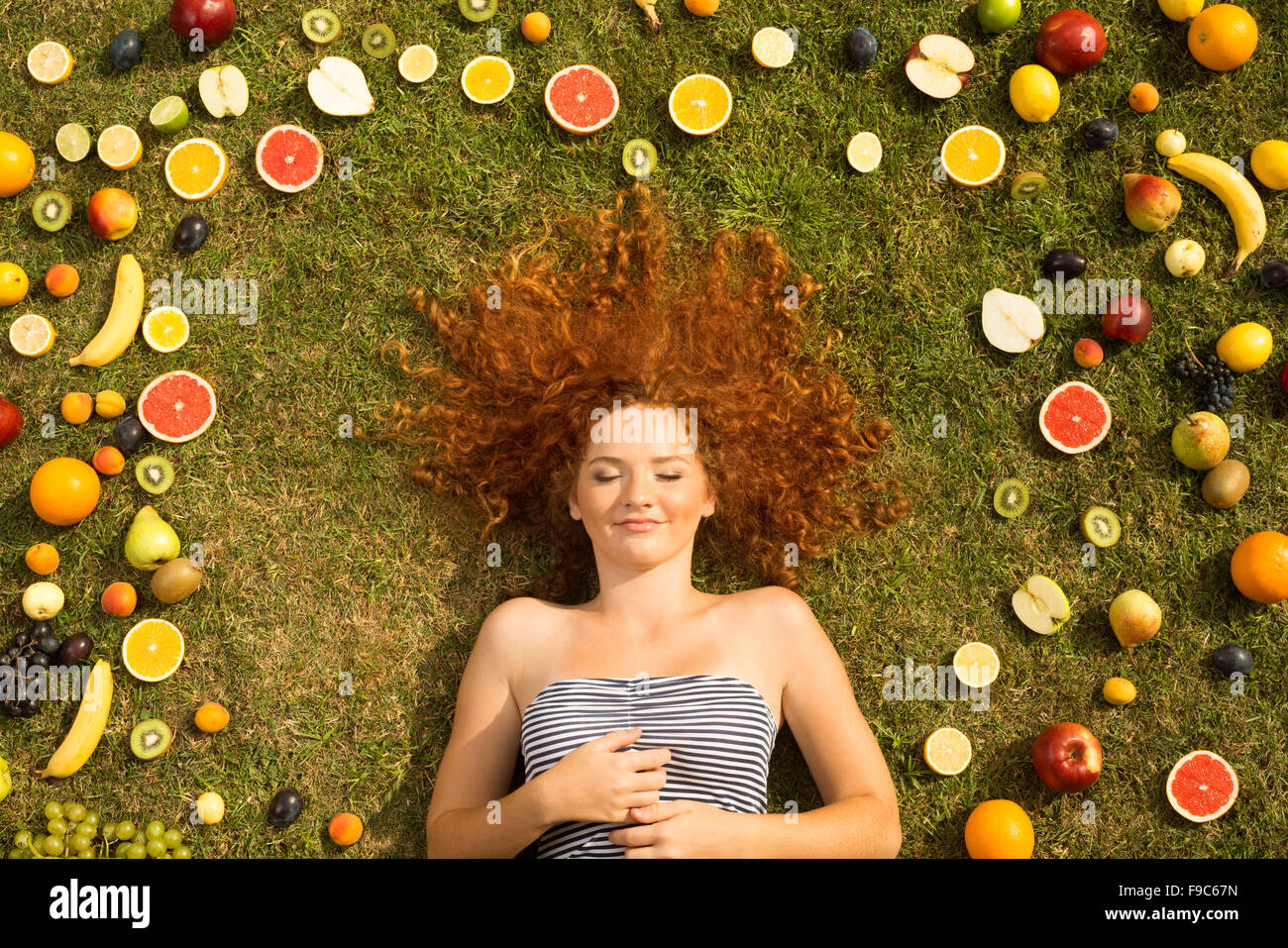 Girl with fruit lying on the grass Stock Photo - Alamy