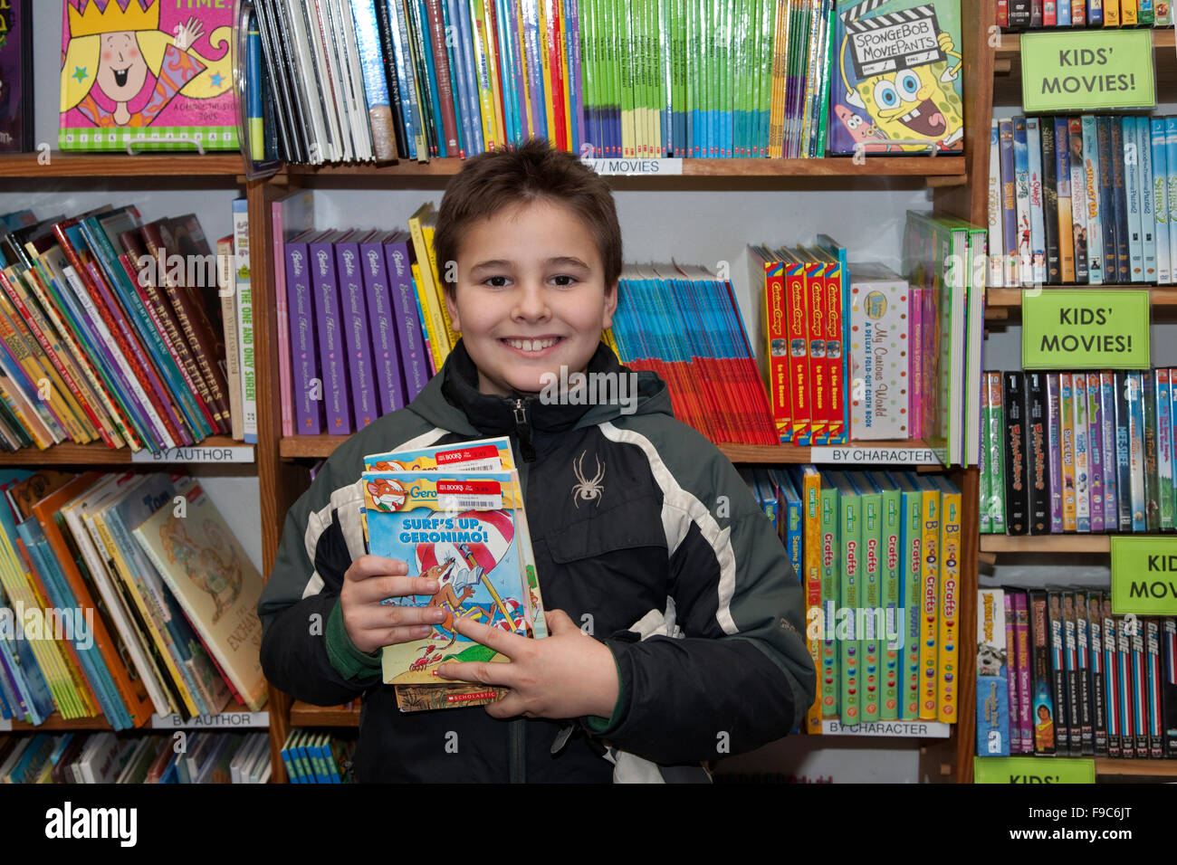 Smiling boy age 9 holding a selection of Geronimo books in a bookstore ...