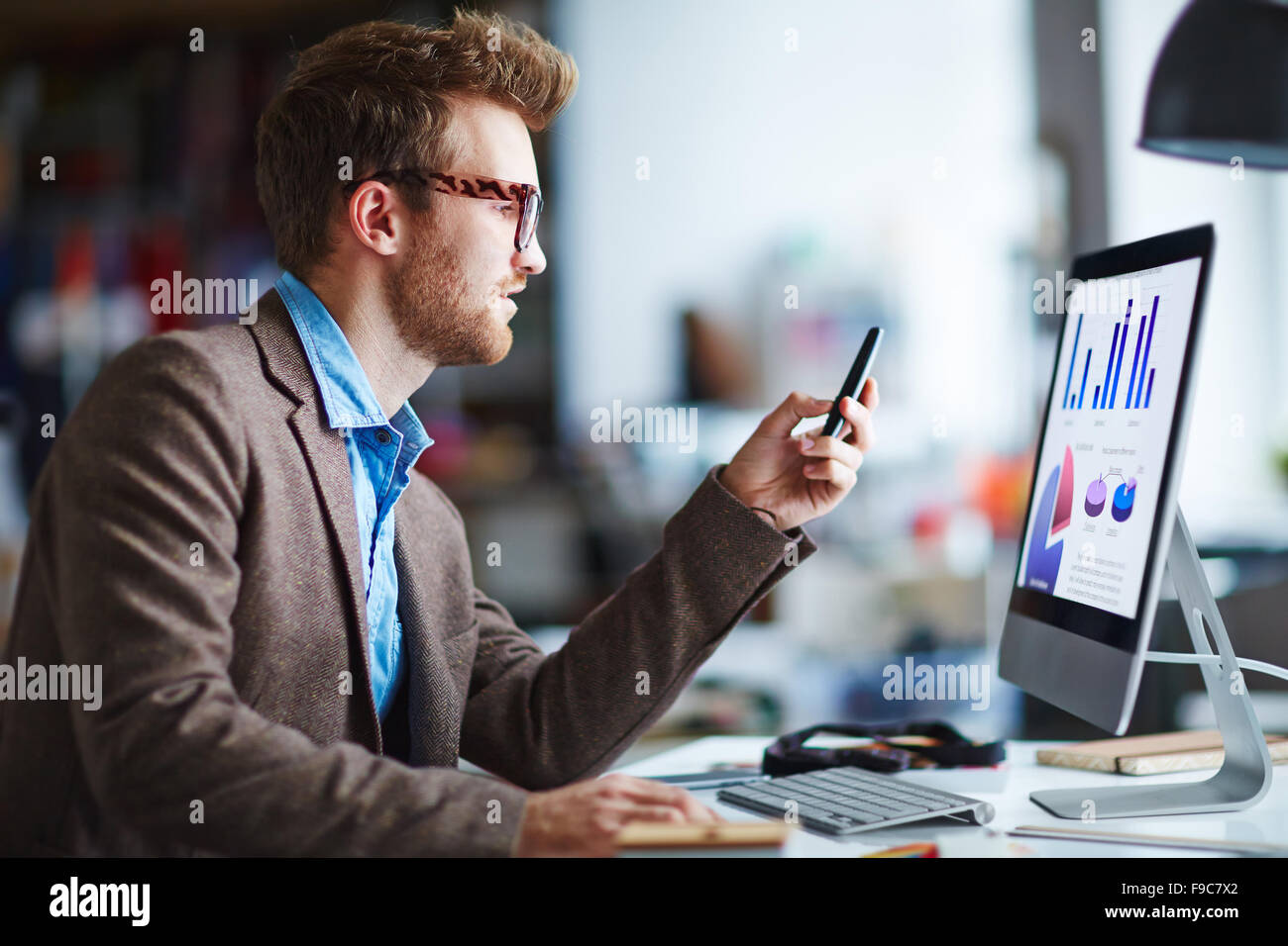 Serious businessman using computer and working with charts at office ...