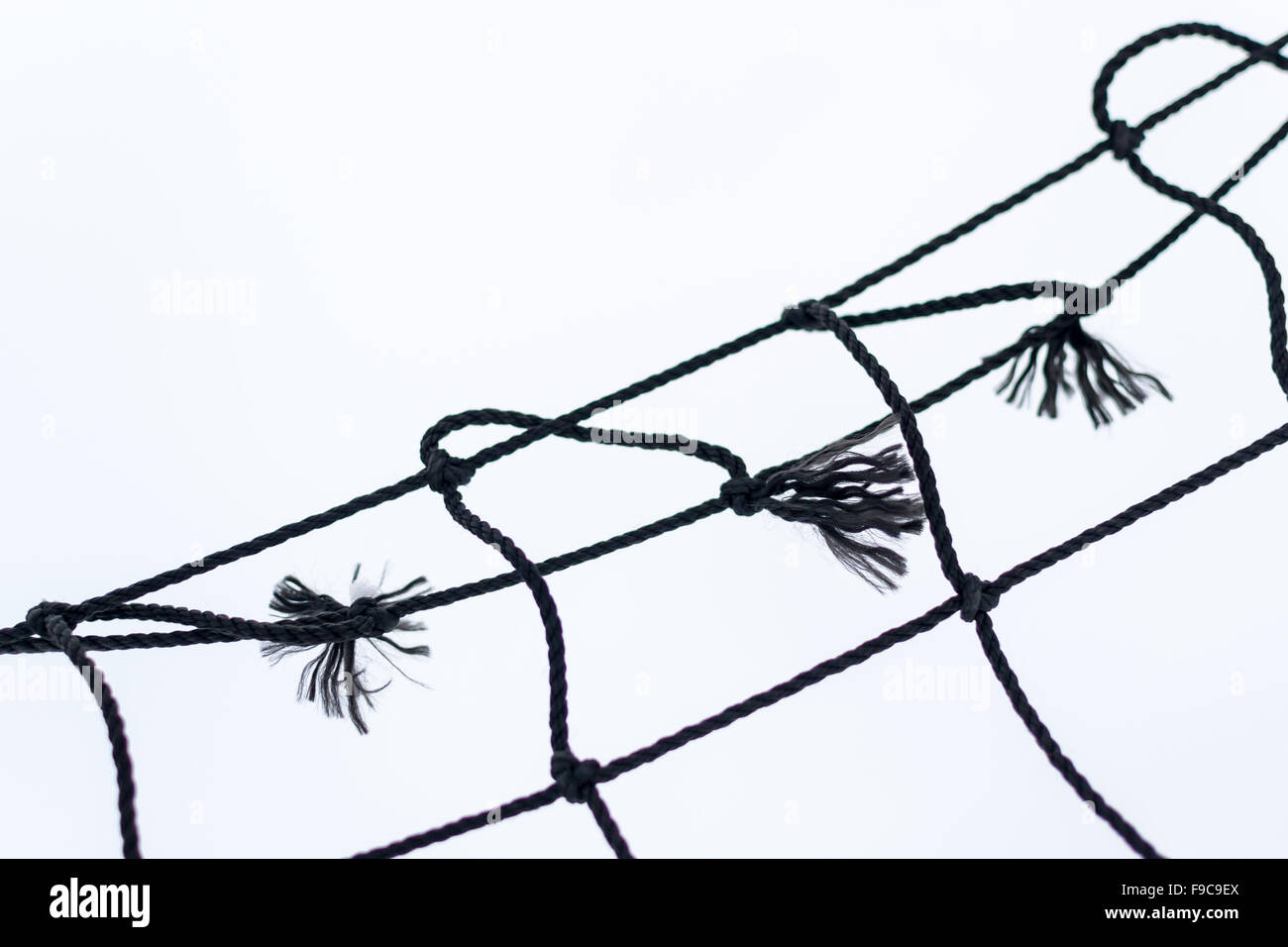 Frayed sports netting at a local public park with a white snow ...