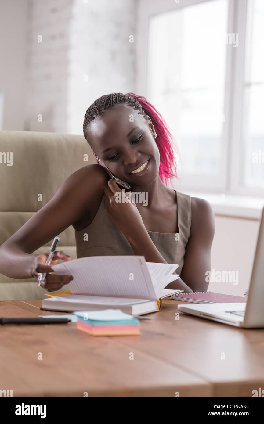 Business woman calling phone and writing something in her schedule book ...