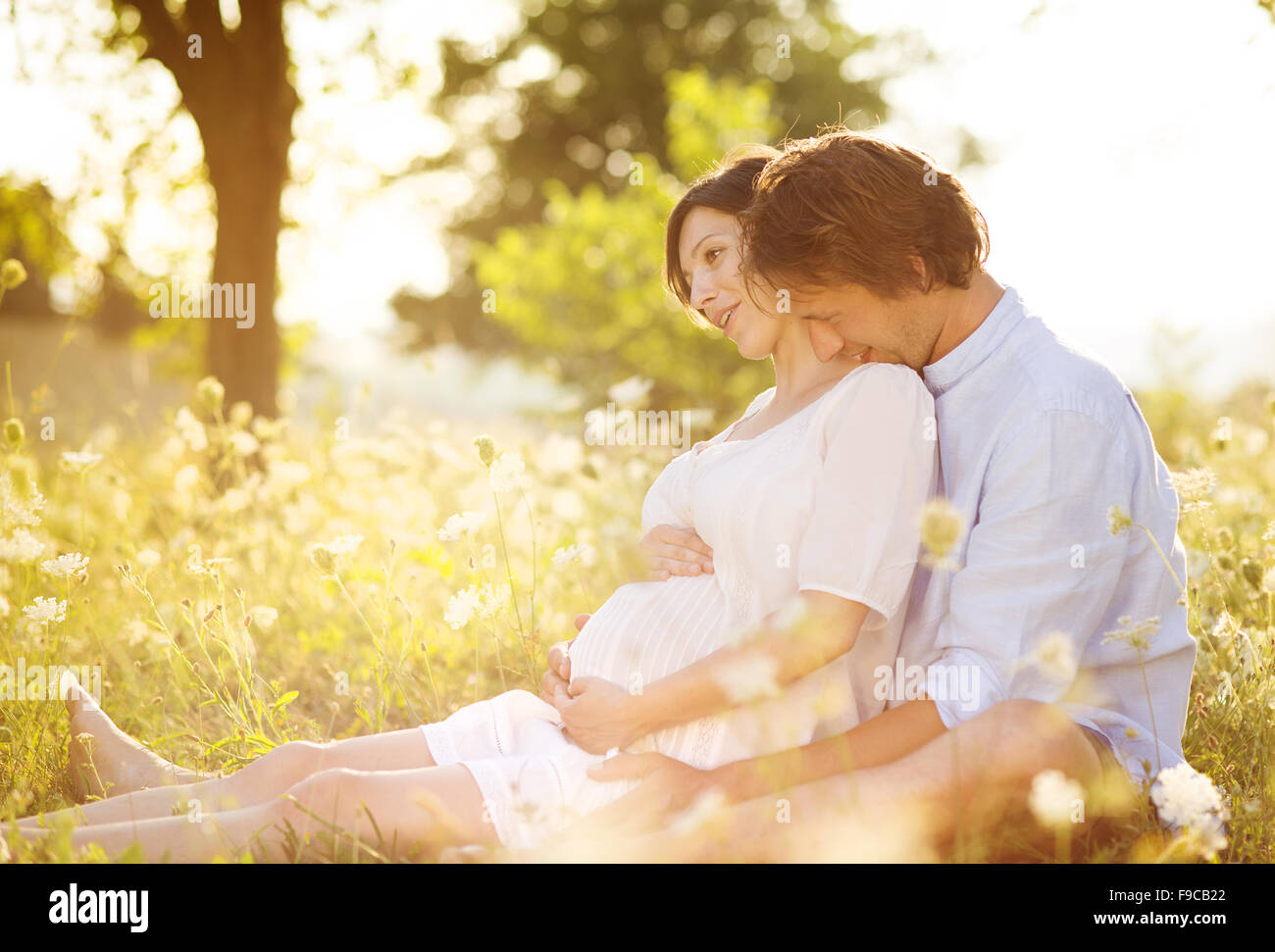 Happy and young pregnant couple hugging in nature Stock Photo - Alamy