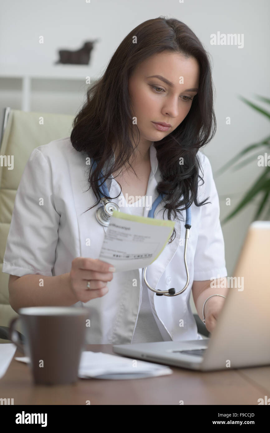 Doctor working with test results and computer at clinic. Filling ...