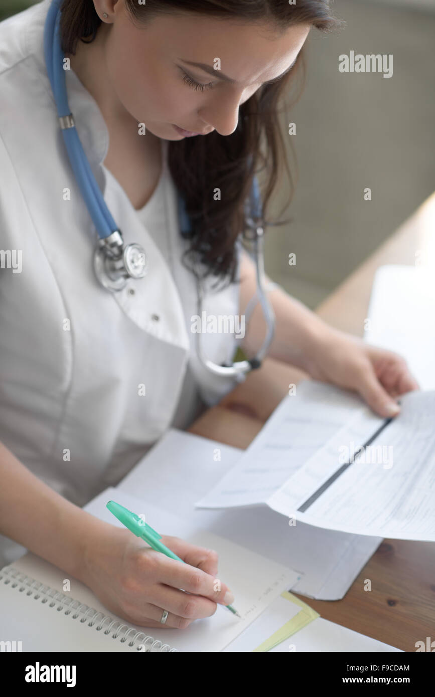 Female doctor taking notes during looking at patient medical tests at ...