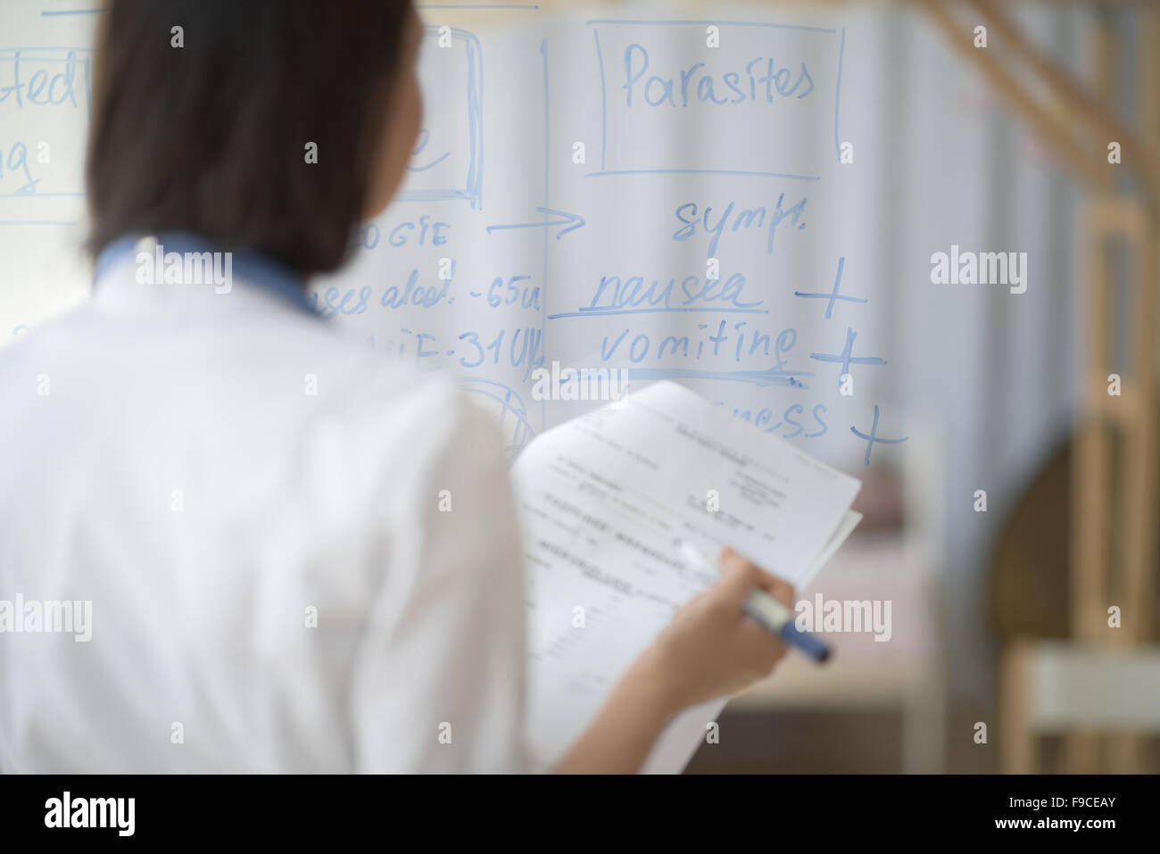 Medical doctor writing patient test results on transparent board to ...