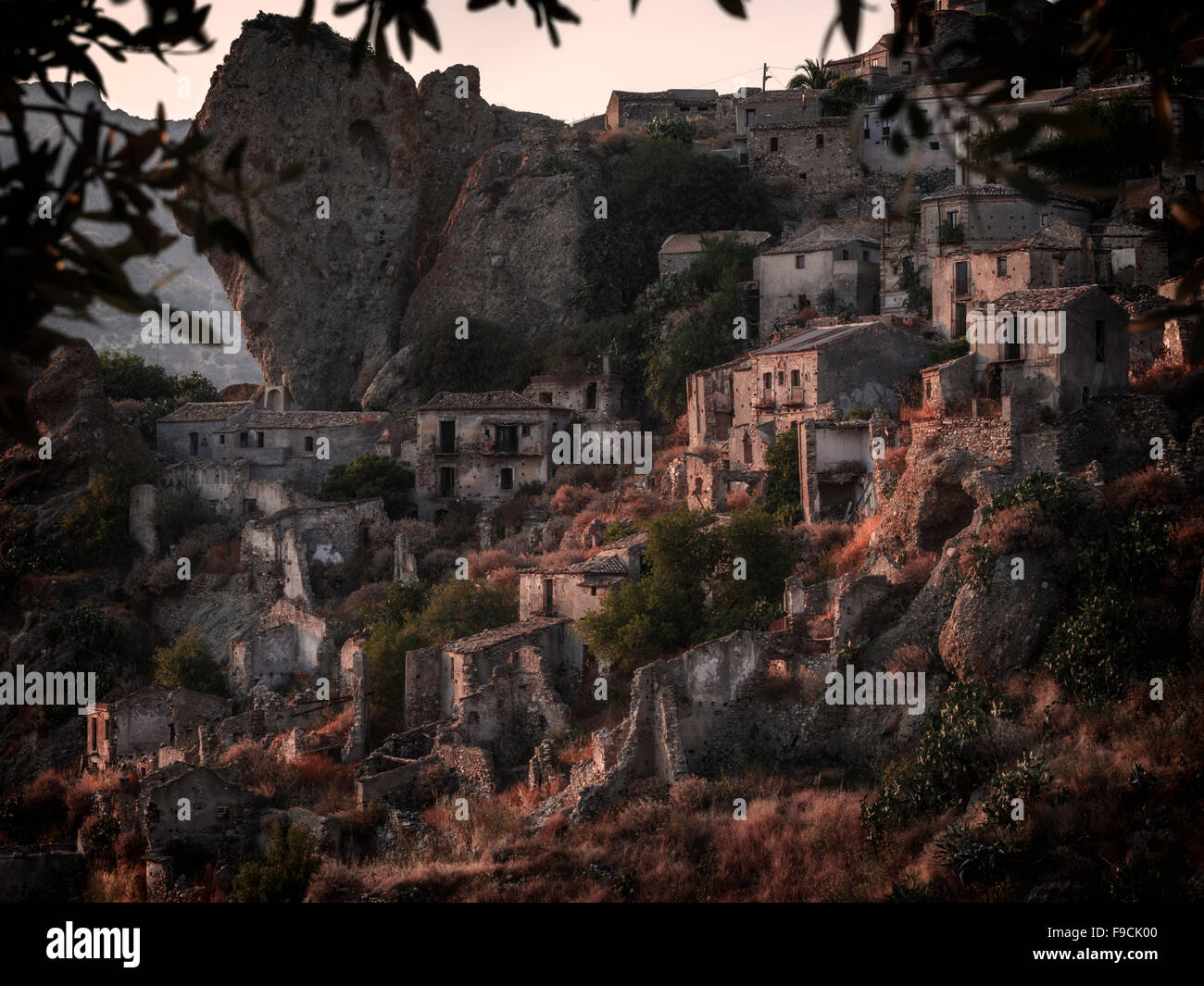 The abandoned village of Pentedattilo at sunset framed by blurred olive ...