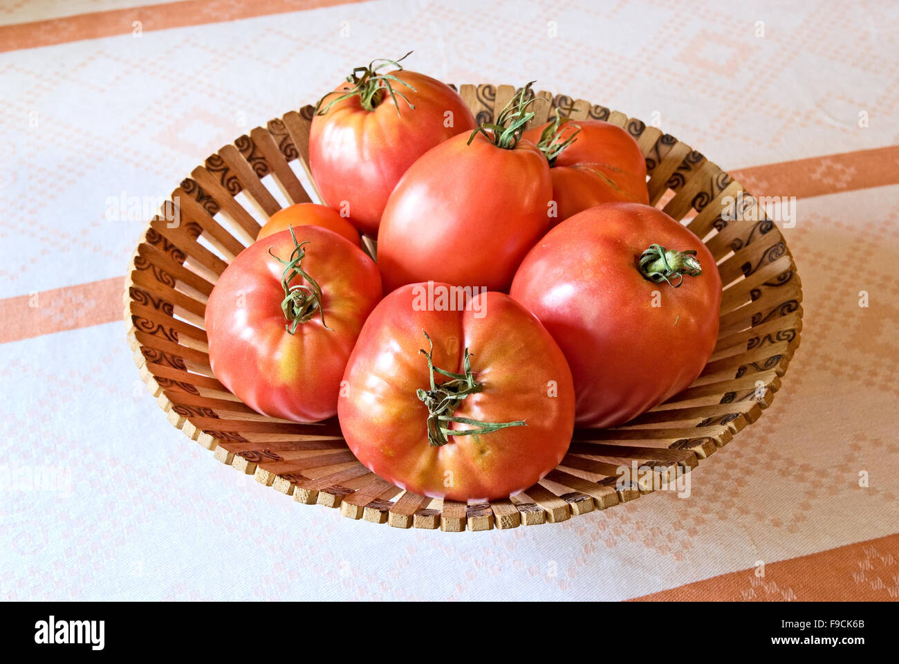 Big red tomatoes in basket on the table Stock Photo - Alamy