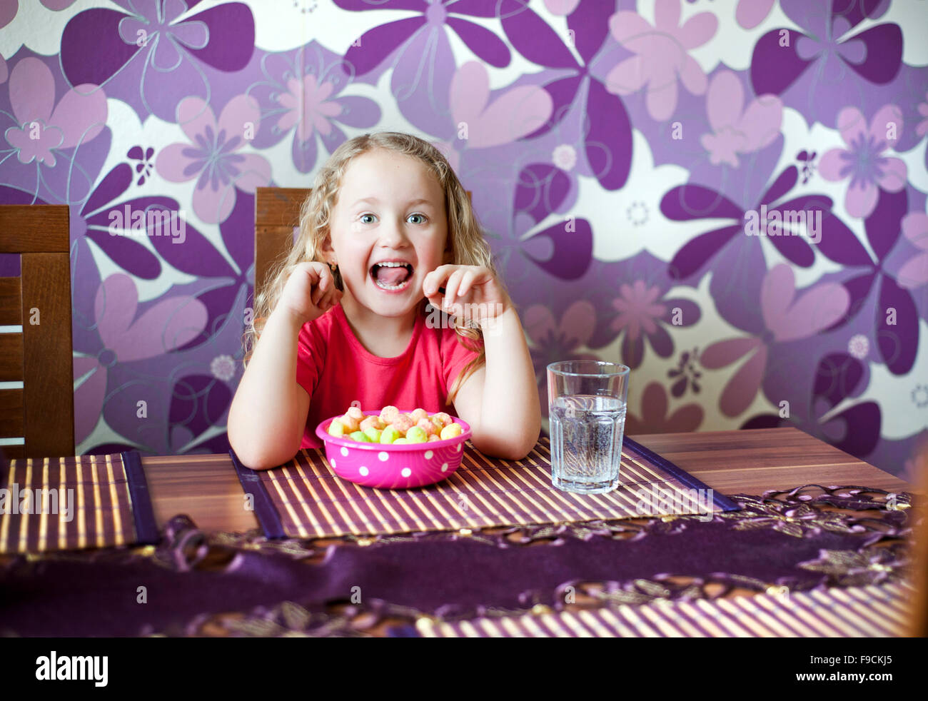 Little girl is eating snack in the kitchen Stock Photo - Alamy