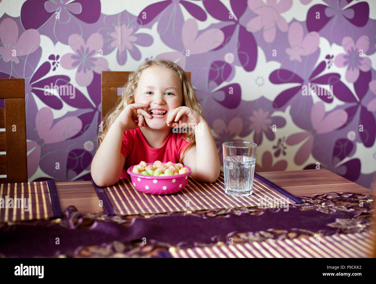Little girl is eating snack in the kitchen Stock Photo - Alamy