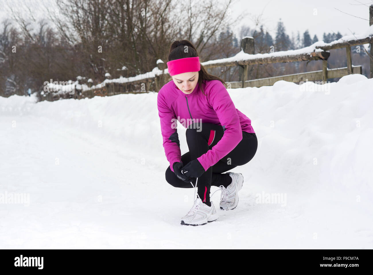 Athlete woman is running during winter training outside in cold snow ...