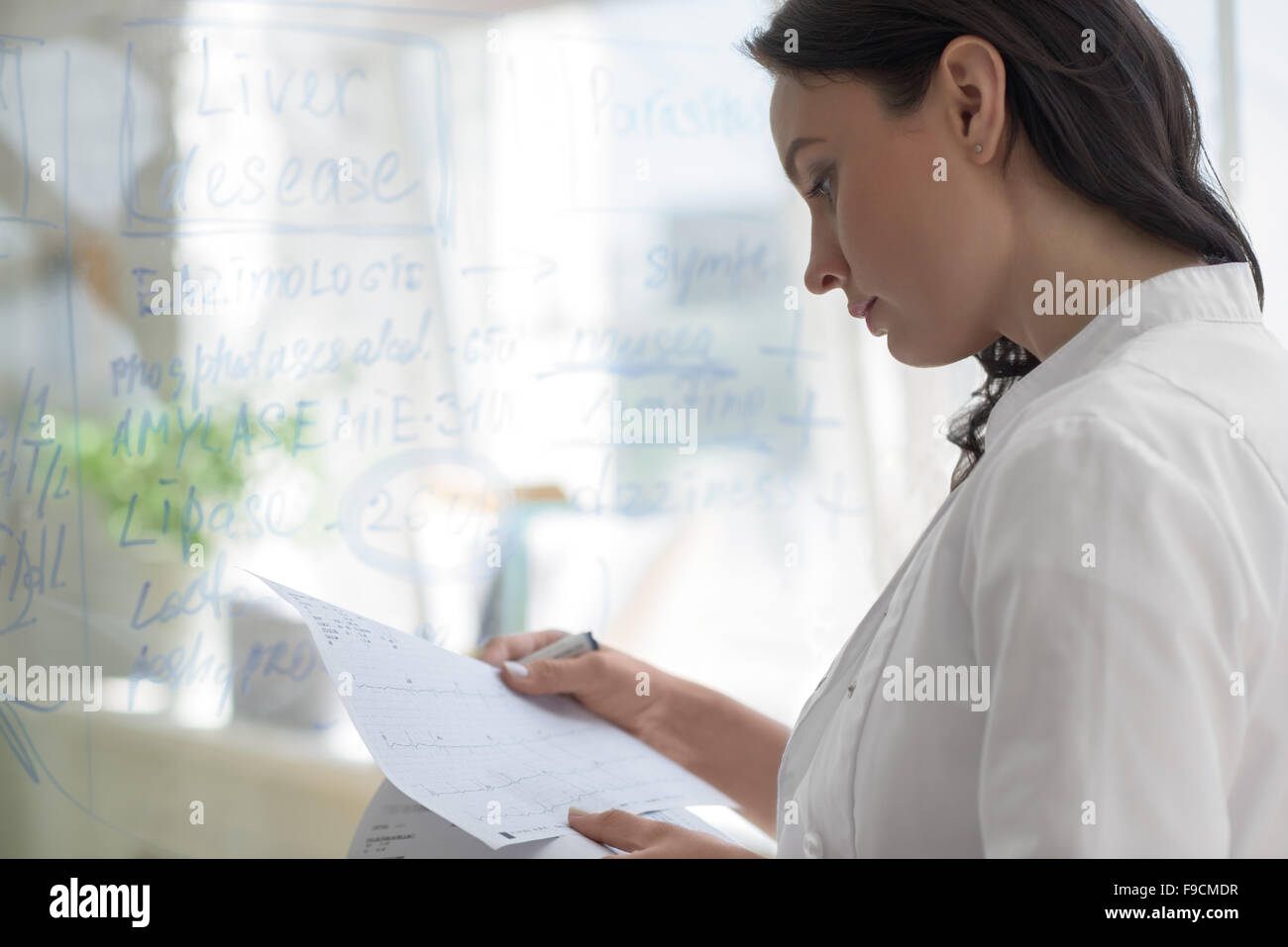 Female medical doctor working at clinic office. Writing on glass ...