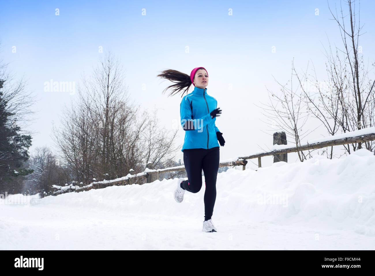 Athlete woman is running during winter training outside in cold snow ...