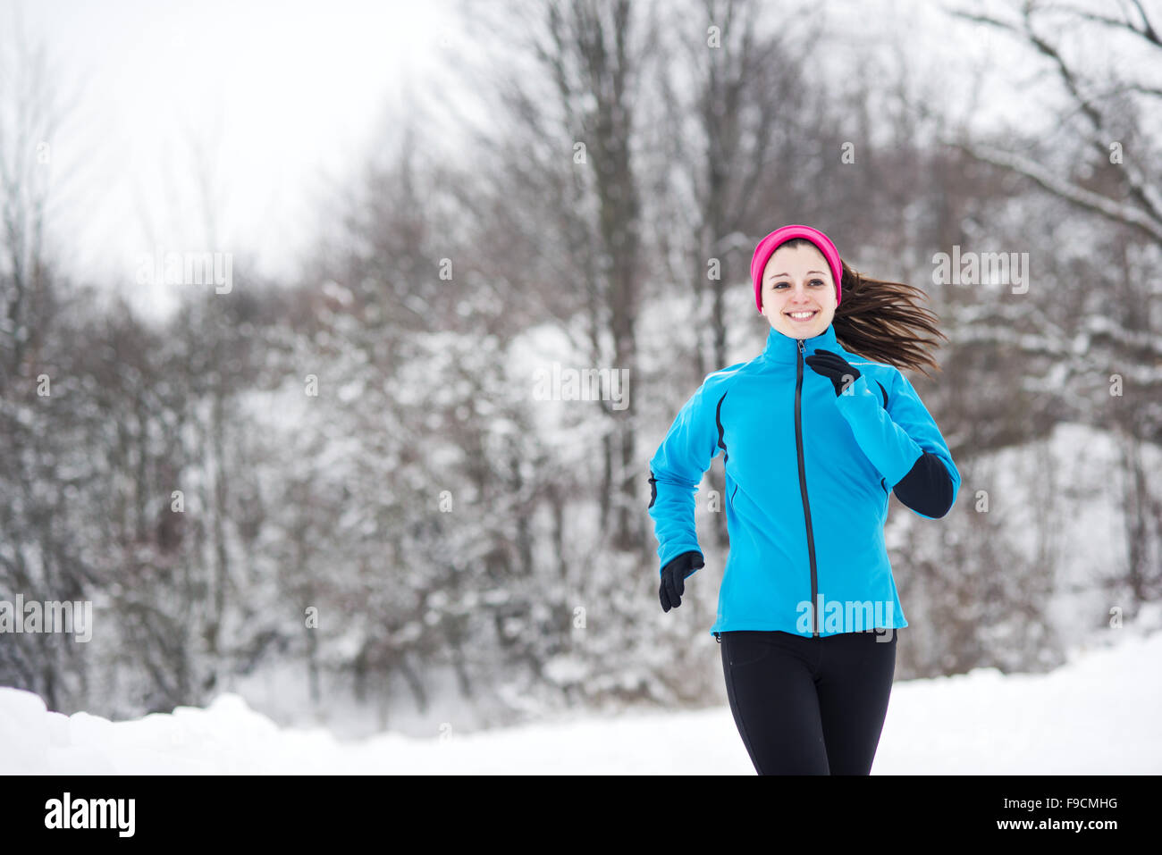 Athlete woman is running during winter training outside in cold snow ...