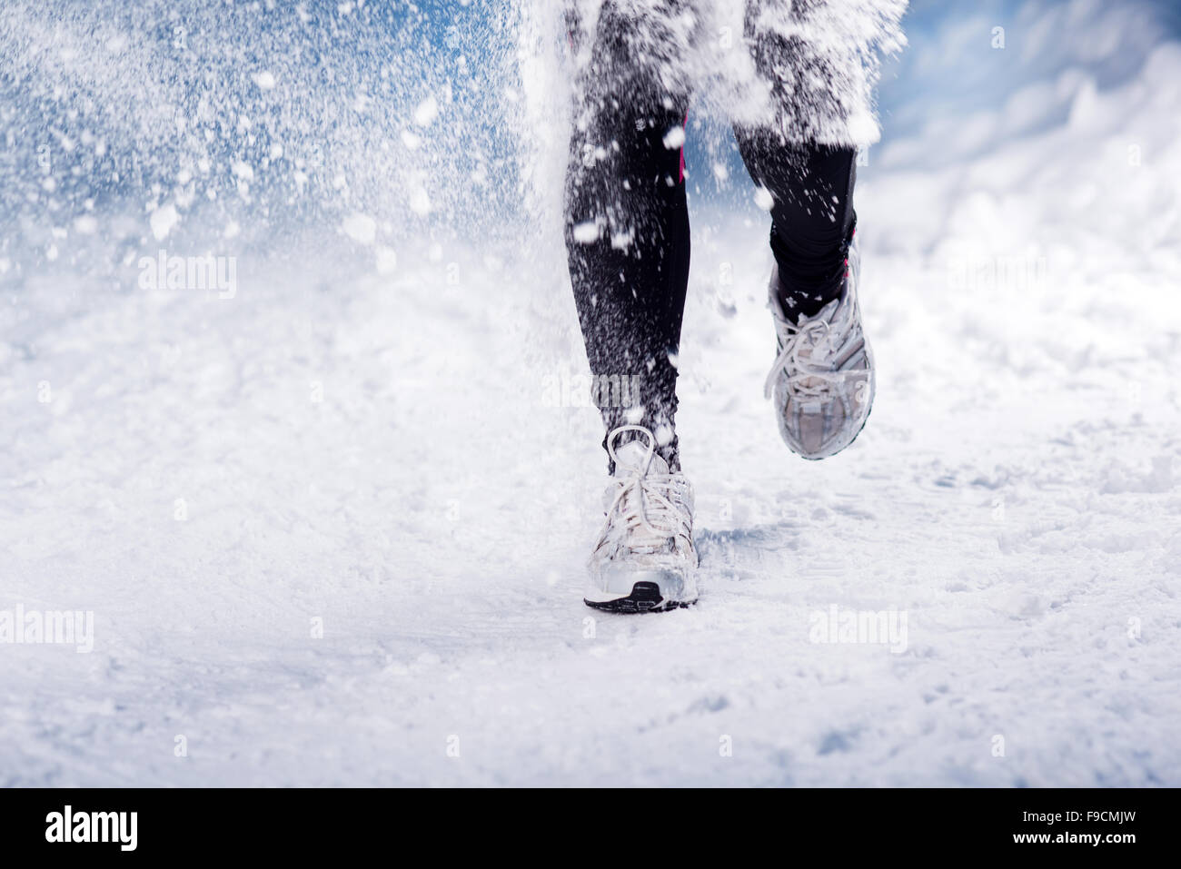 Athlete woman is running during winter training outside in cold snow ...
