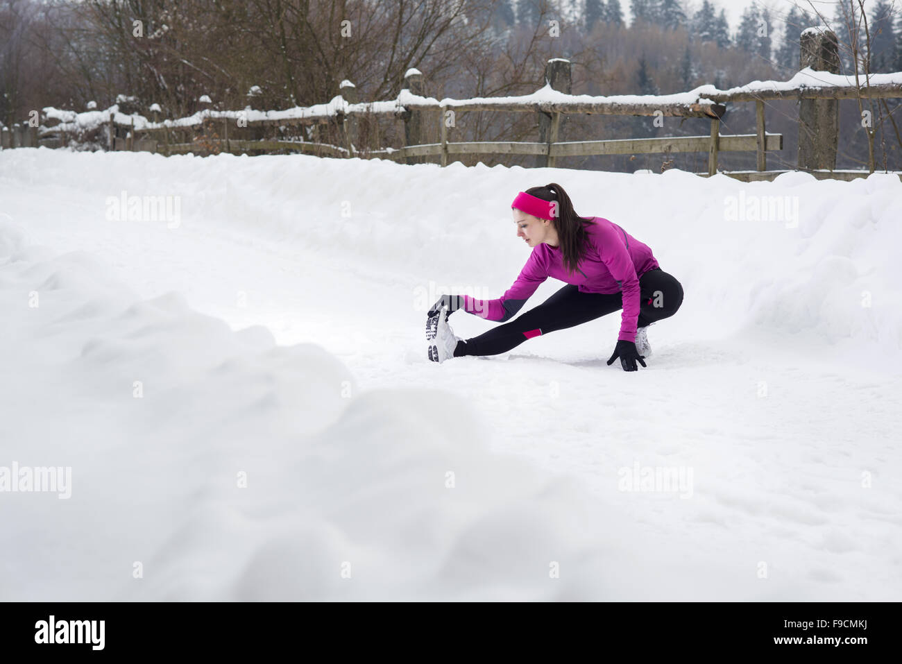 Athlete woman is running during winter training outside in cold snow ...