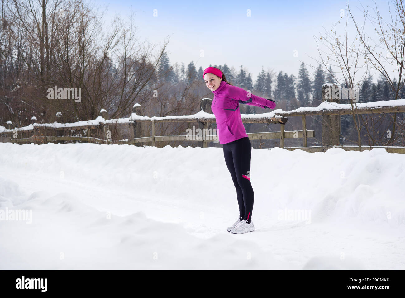 Athlete woman is running during winter training outside in cold snow ...