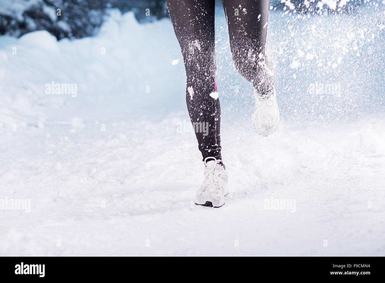 Athlete woman is running during winter training outside in cold snow ...