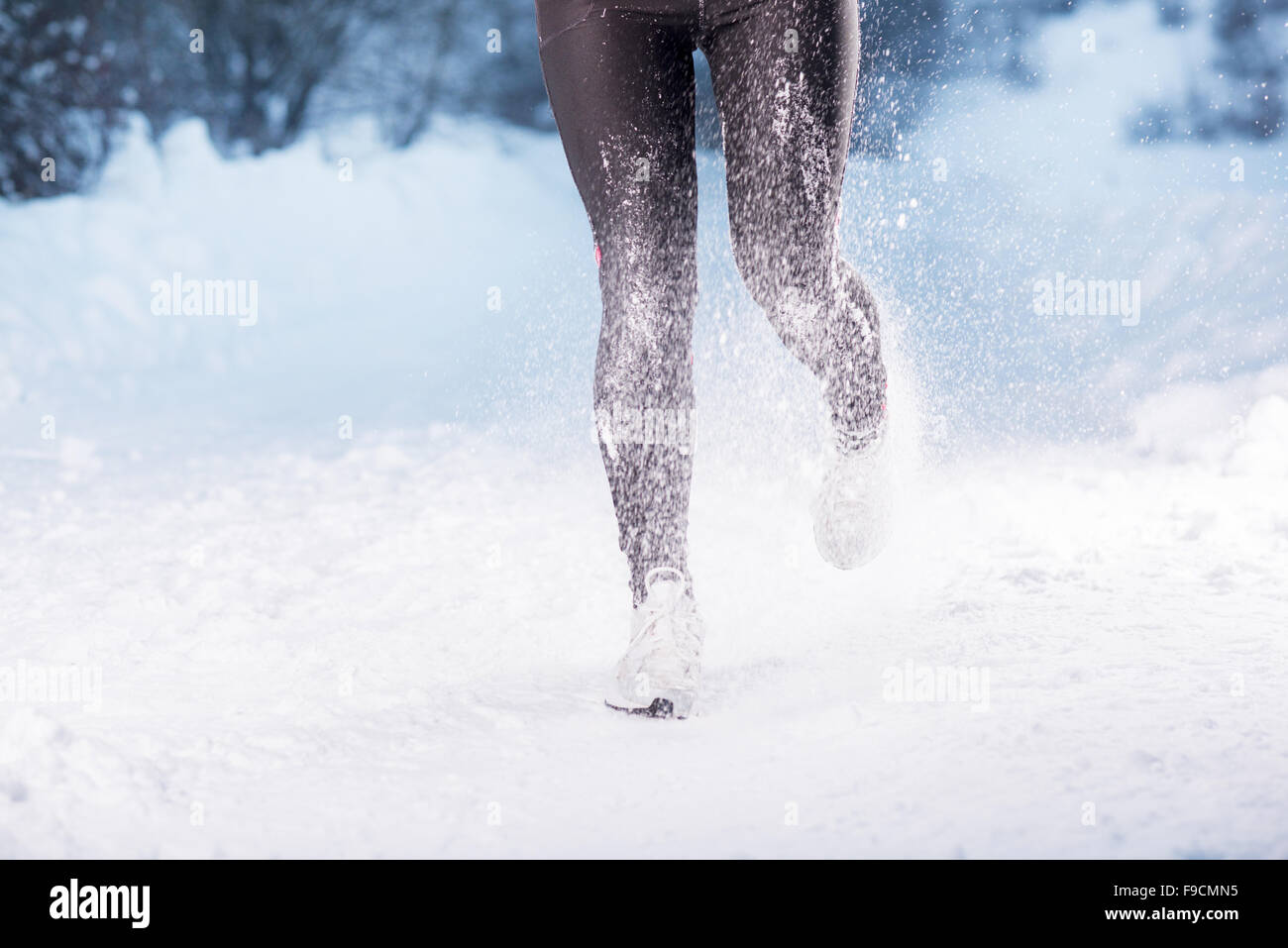 Athlete woman is running during winter training outside in cold snow ...