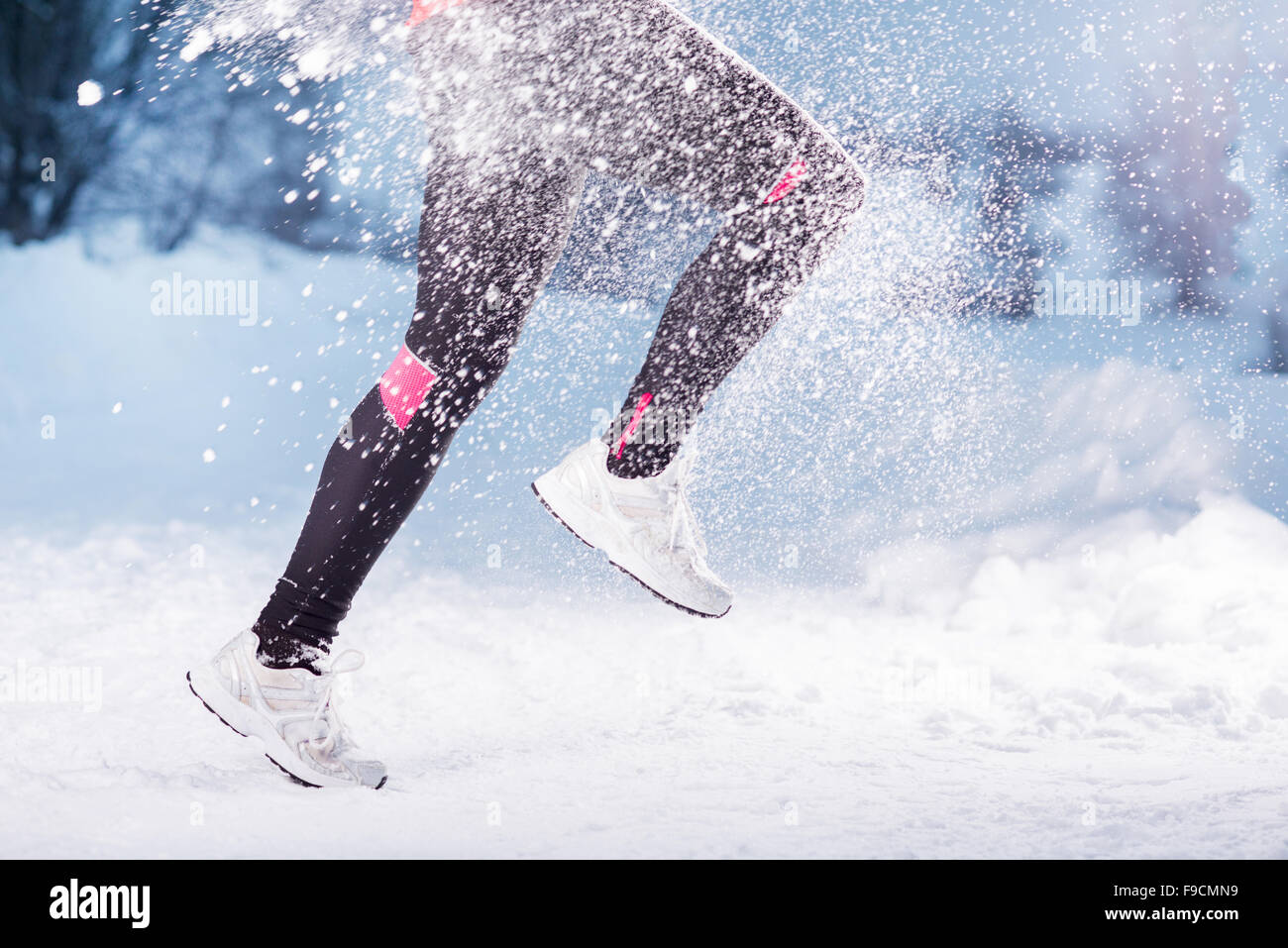Athlete woman is running during winter training outside in cold snow ...