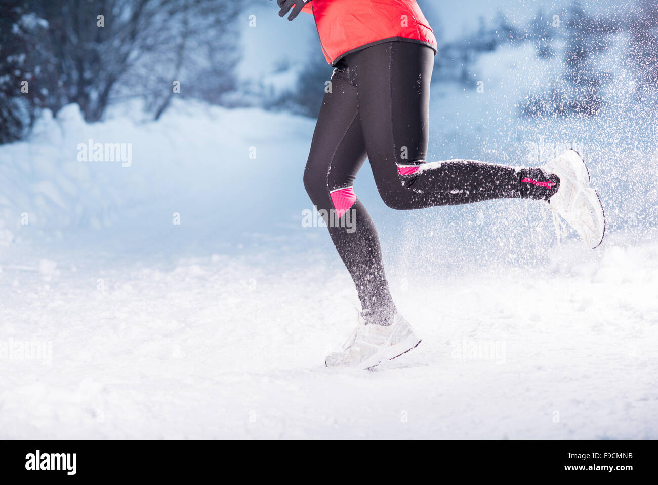 Athlete woman is running during winter training outside in cold snow ...