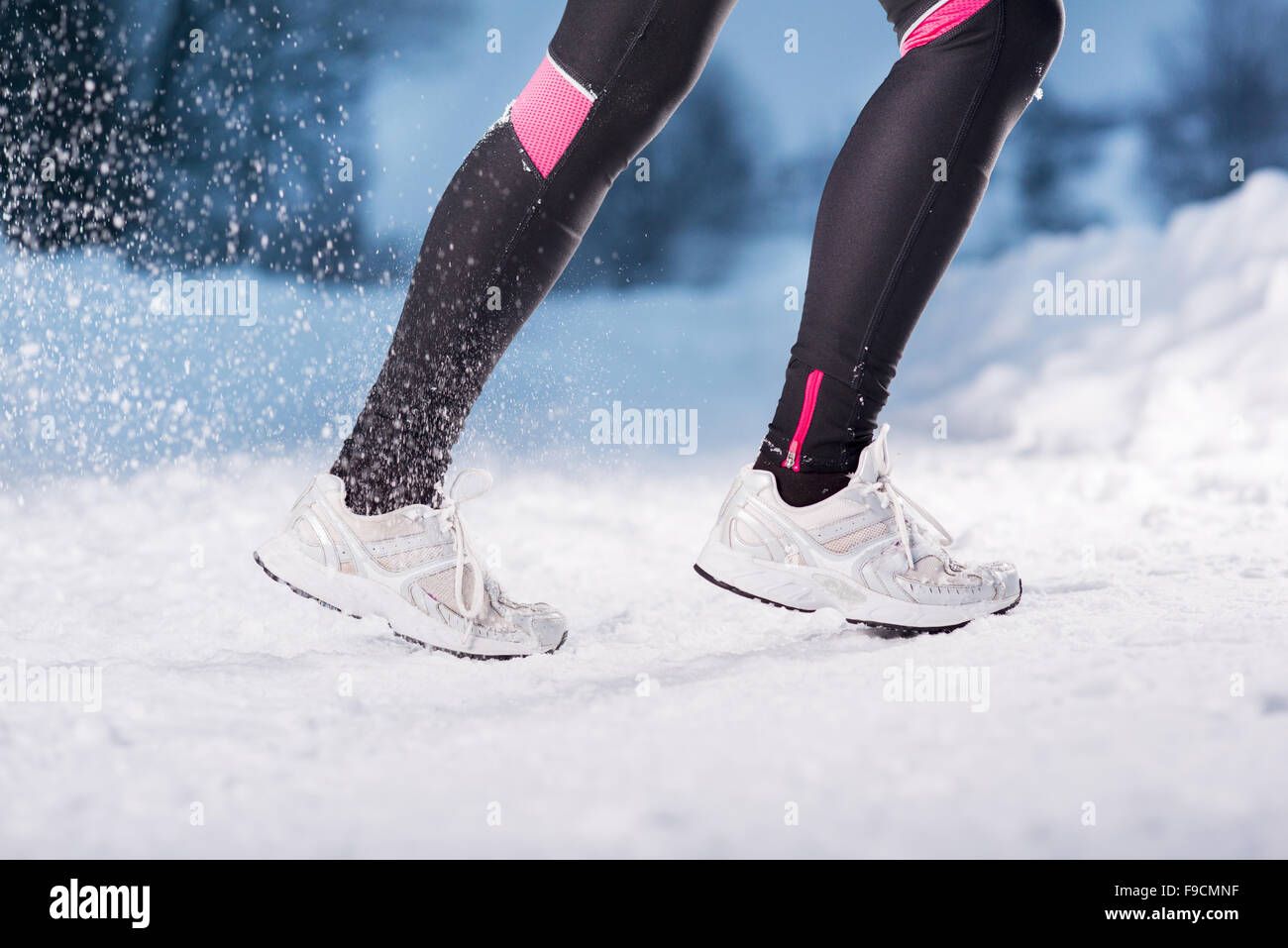 Athlete woman is running during winter training outside in cold snow ...