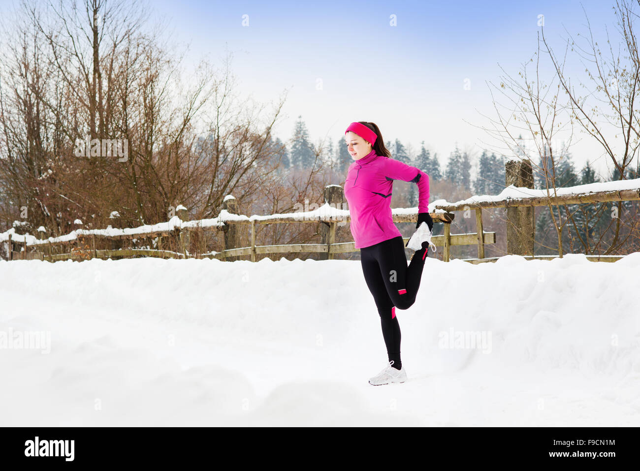 Athlete woman is running during winter training outside in cold snow ...