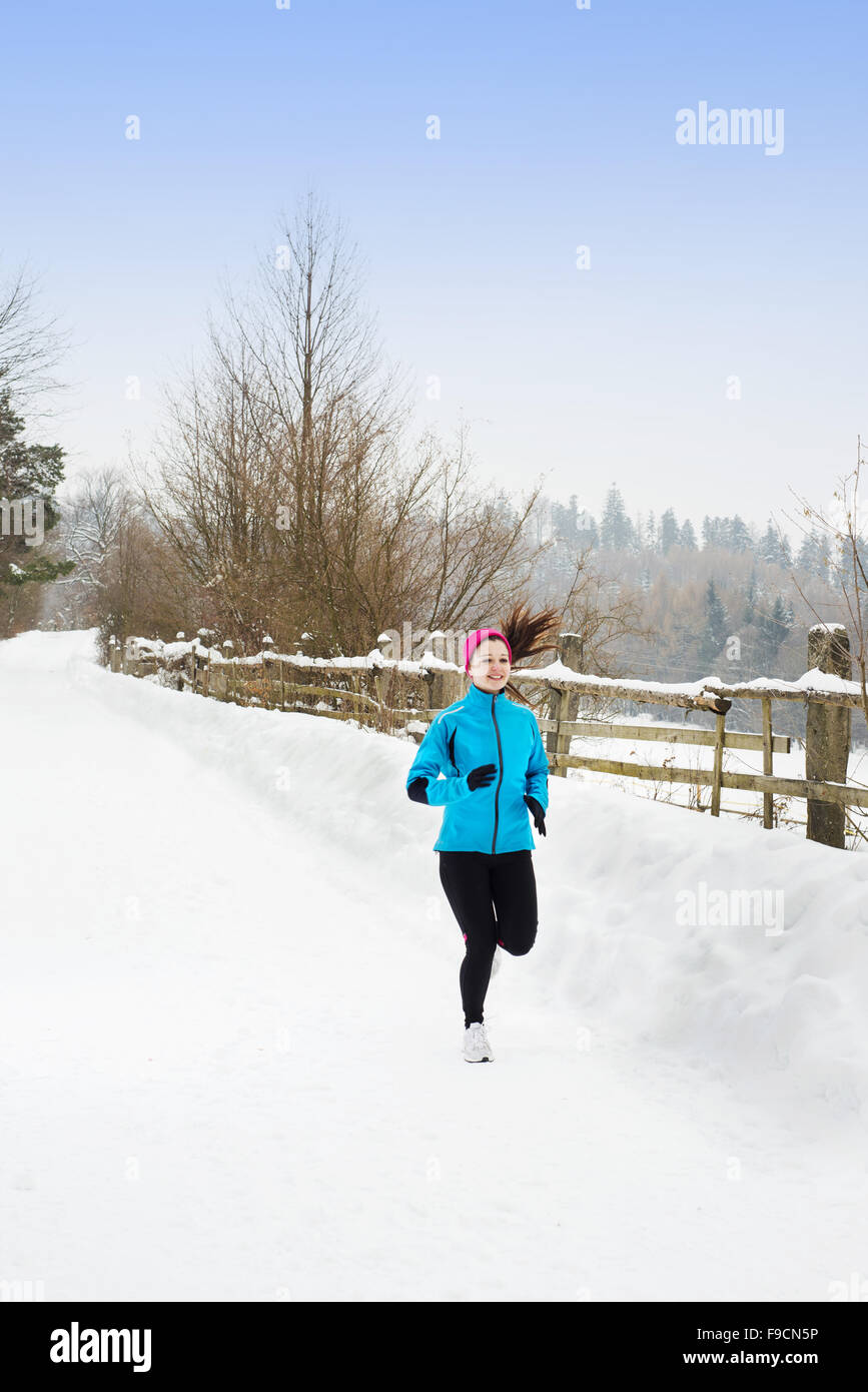 Athlete woman is running during winter training outside in cold snow ...