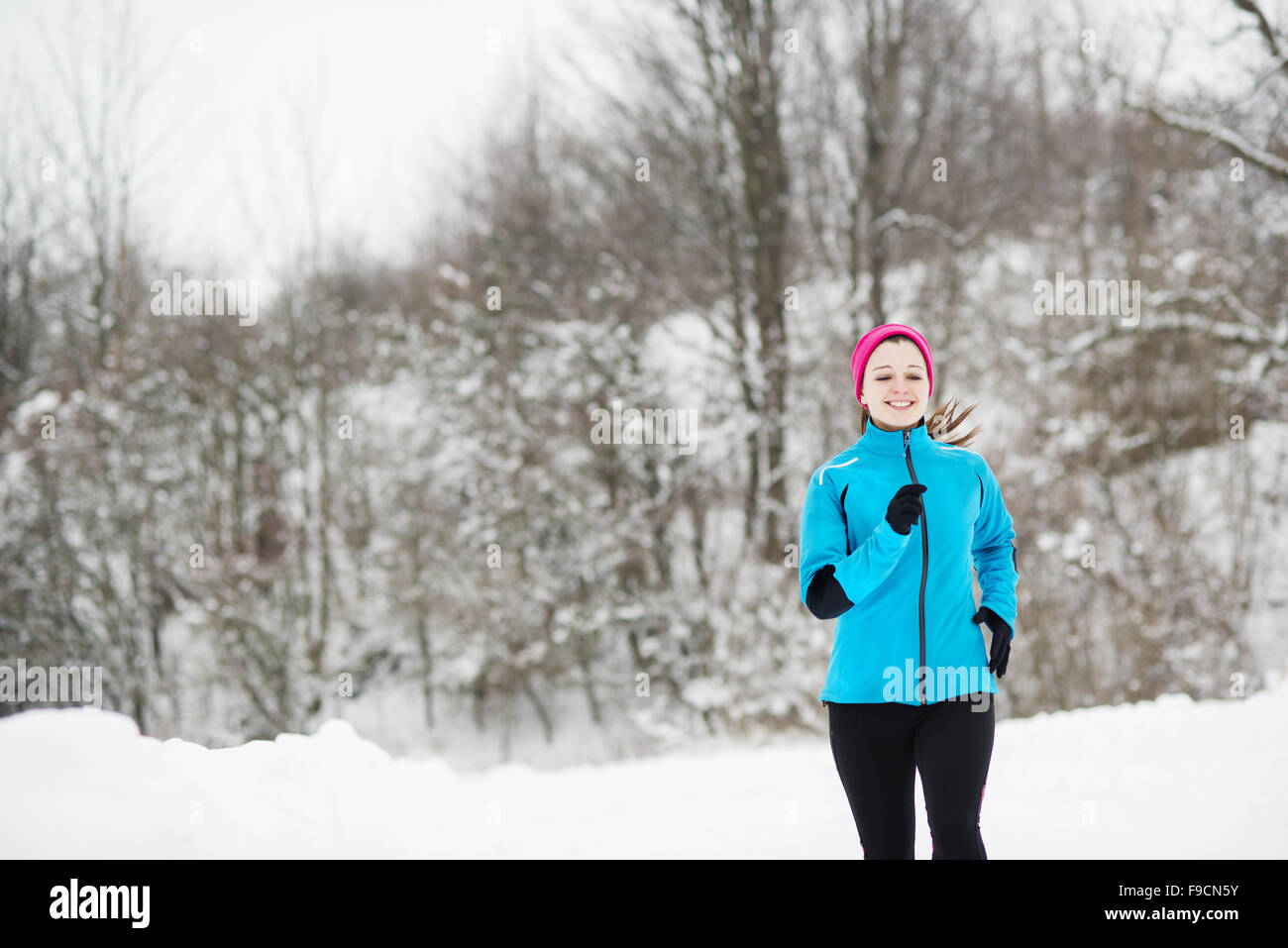 Athlete woman is running during winter training outside in cold snow ...