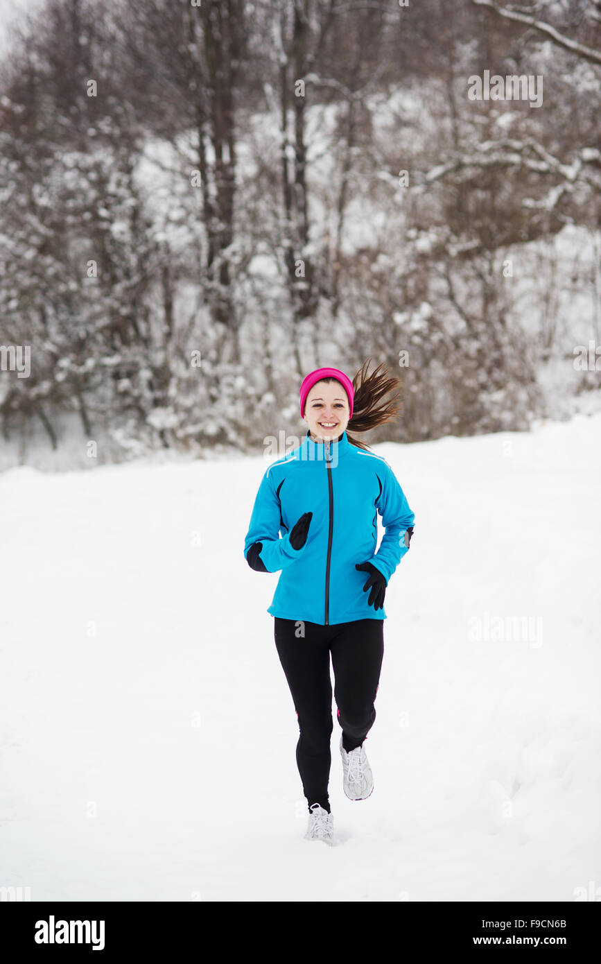 Athlete woman is running during winter training outside in cold snow ...