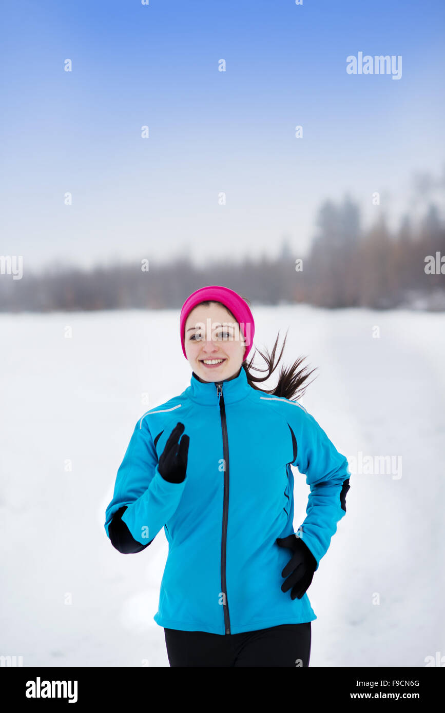 Athlete woman is running during winter training outside in cold snow ...