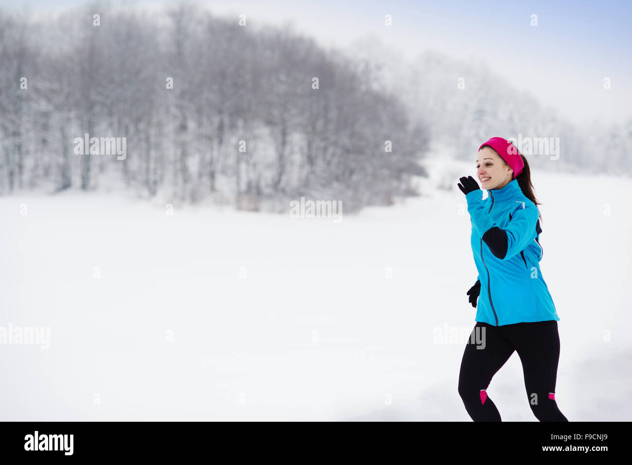 Athlete woman is running during winter training outside in cold snow ...