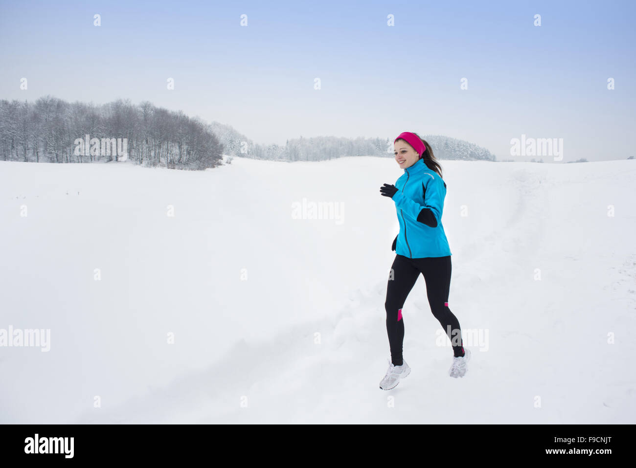 Athlete woman is running during winter training outside in cold snow ...