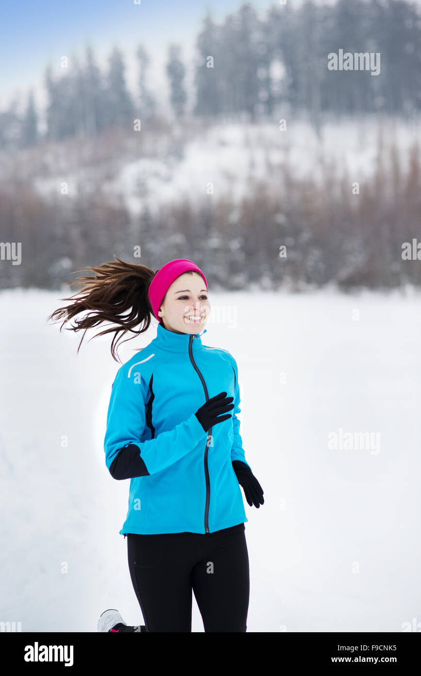 Athlete woman is running during winter training outside in cold snow ...