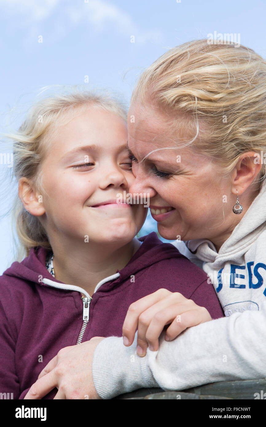 A mother and a daughter hugging and nuzzling against a blue sky Stock ...