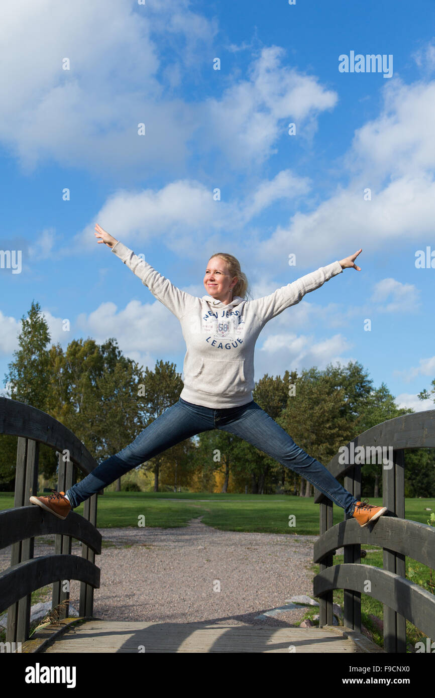 Woman standing on a brigde railing with raised hands Stock Photo - Alamy