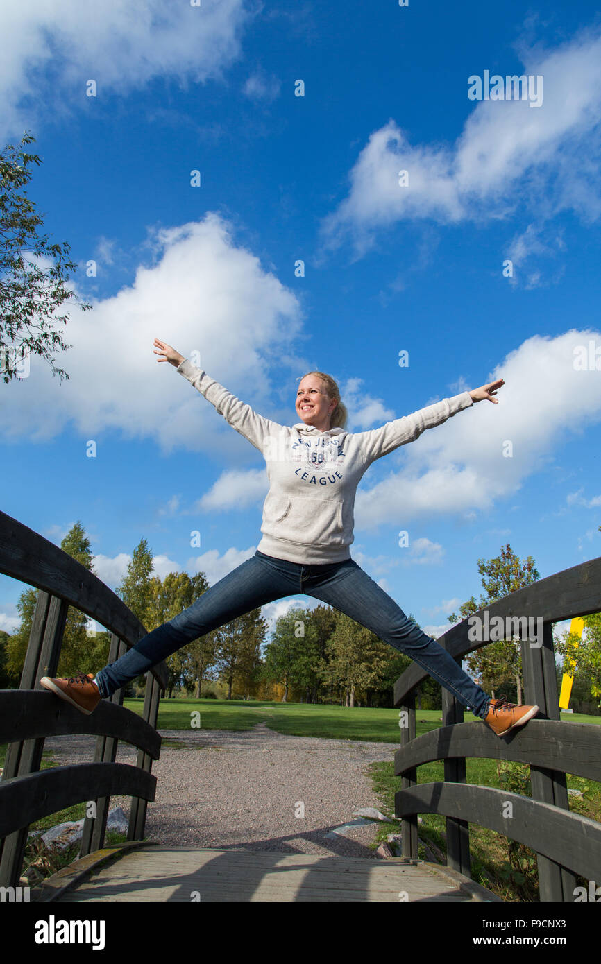Woman standing on a brigde railing with raised hands Stock Photo - Alamy