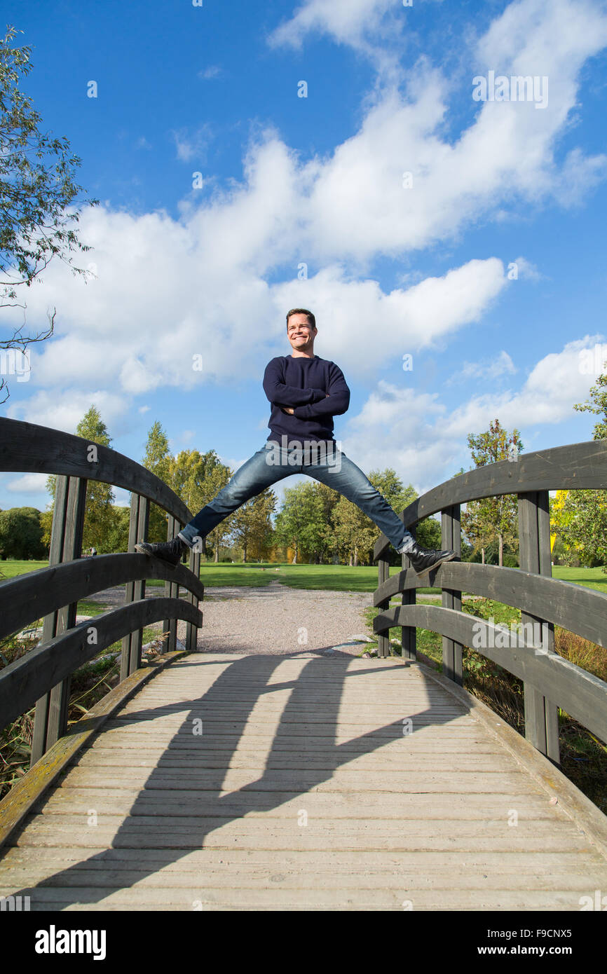 A man standing on a bridge railing victoriously smiling Stock Photo - Alamy