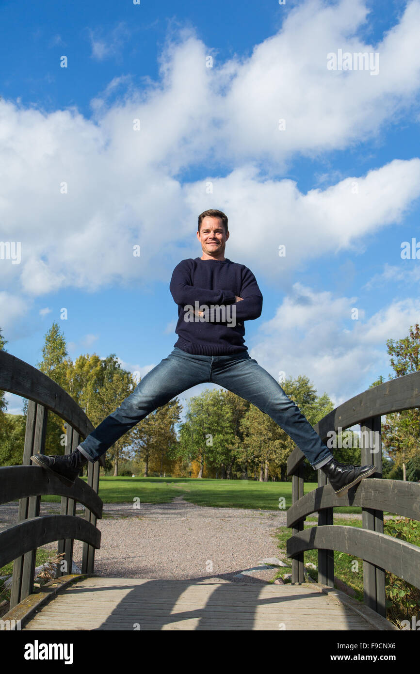 A man standing on a bridge railing victoriously smiling Stock Photo - Alamy
