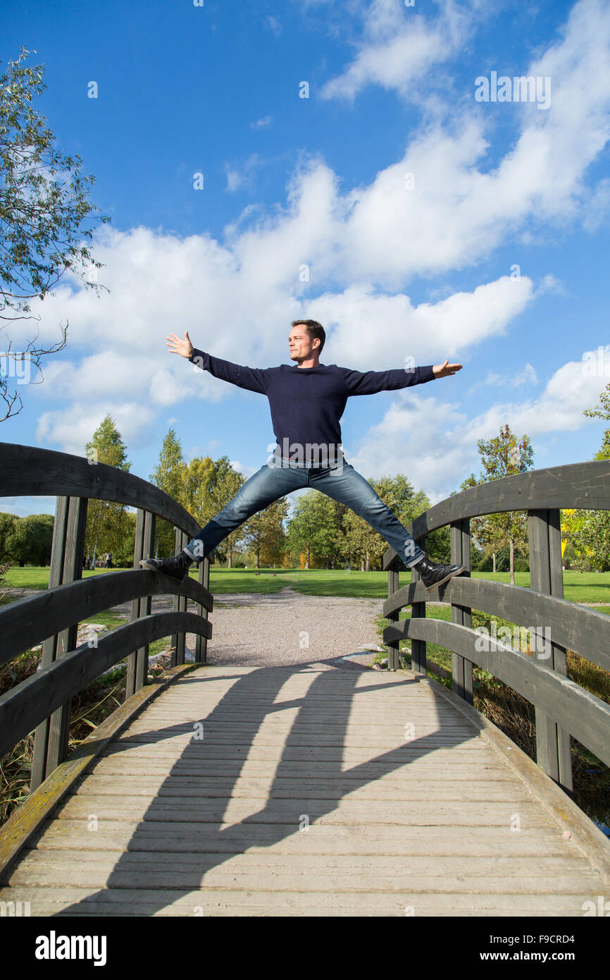 A man standing on a bridge railing victoriously smiling Stock Photo - Alamy