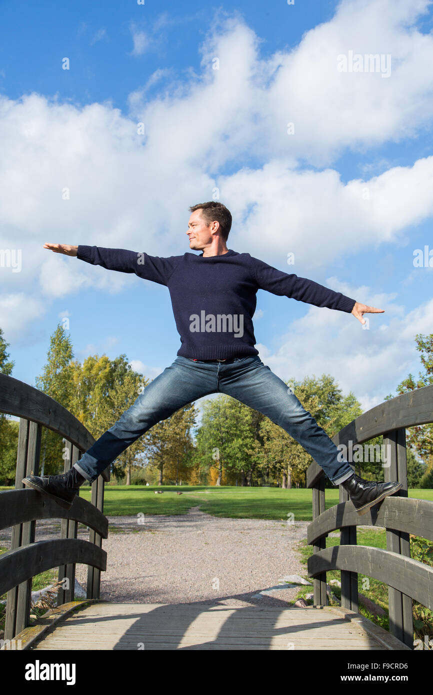 A man standing on a bridge railing victoriously smiling Stock Photo - Alamy