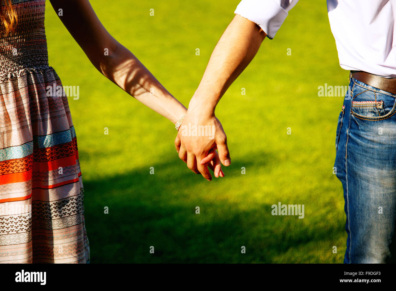 Couple holding hands on the background of green grass Stock Photo - Alamy