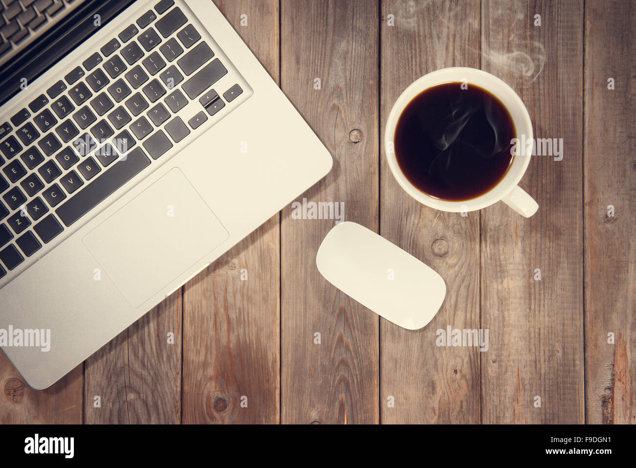 Wooden work table with laptop, cup of hot coffee, in dramatic light ...
