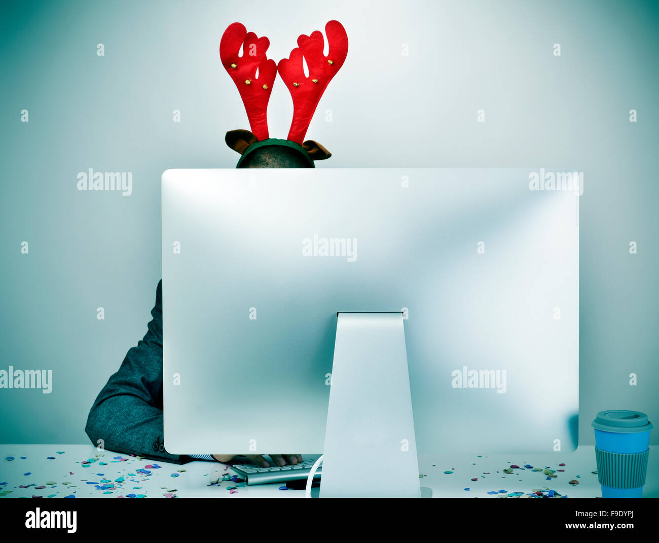 a young caucasian businessman with a reindeer antlers headband, behind ...