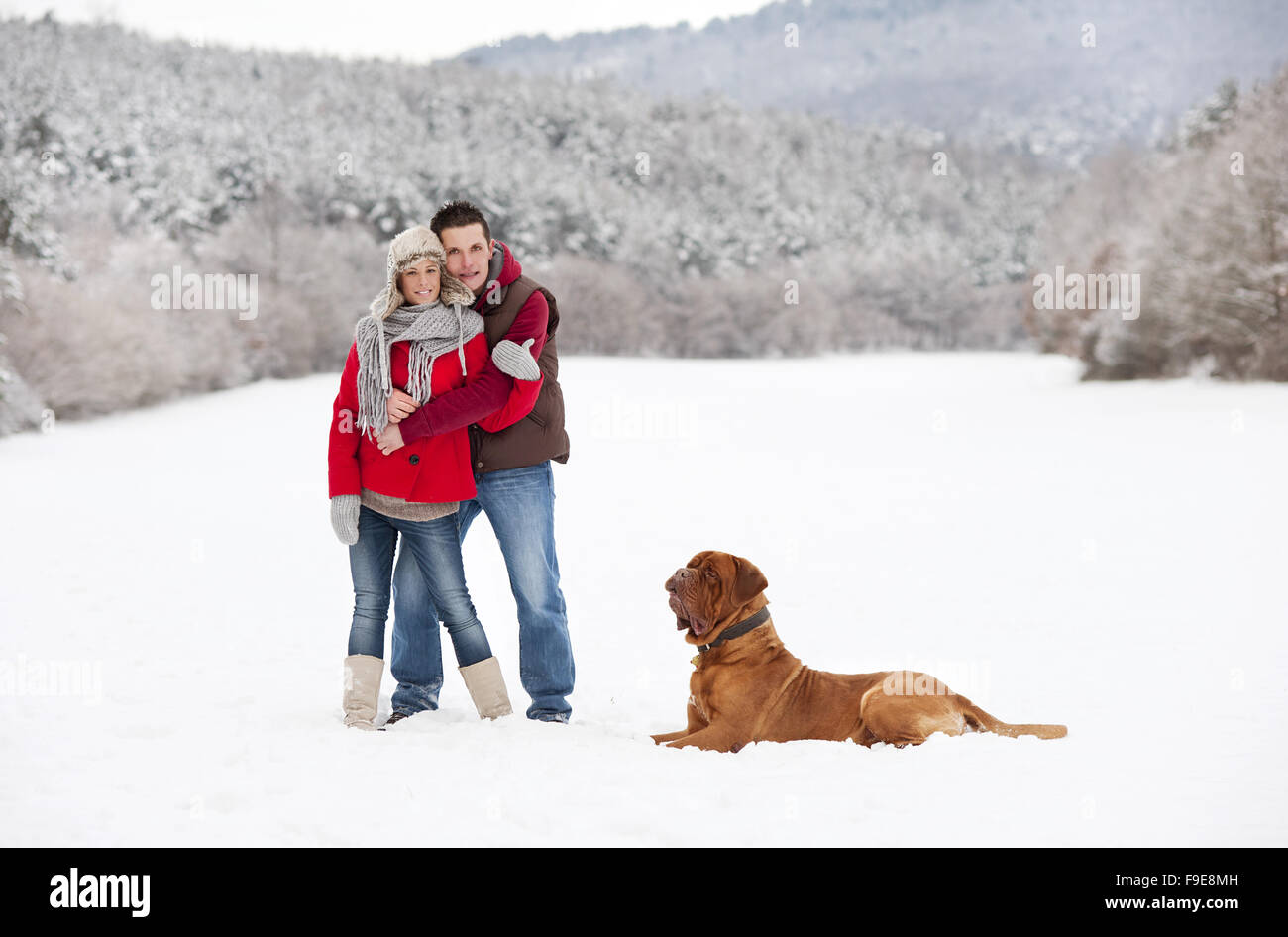 Woman and man are having walk with dog in winter snowy countryside ...